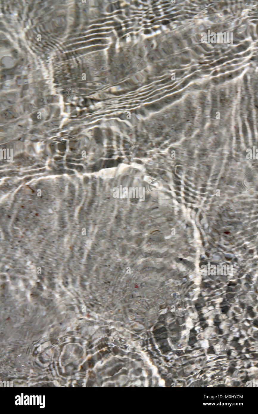 Clear shallow water surface on beach, on the shore of Ile Aux Cerfs, a ...