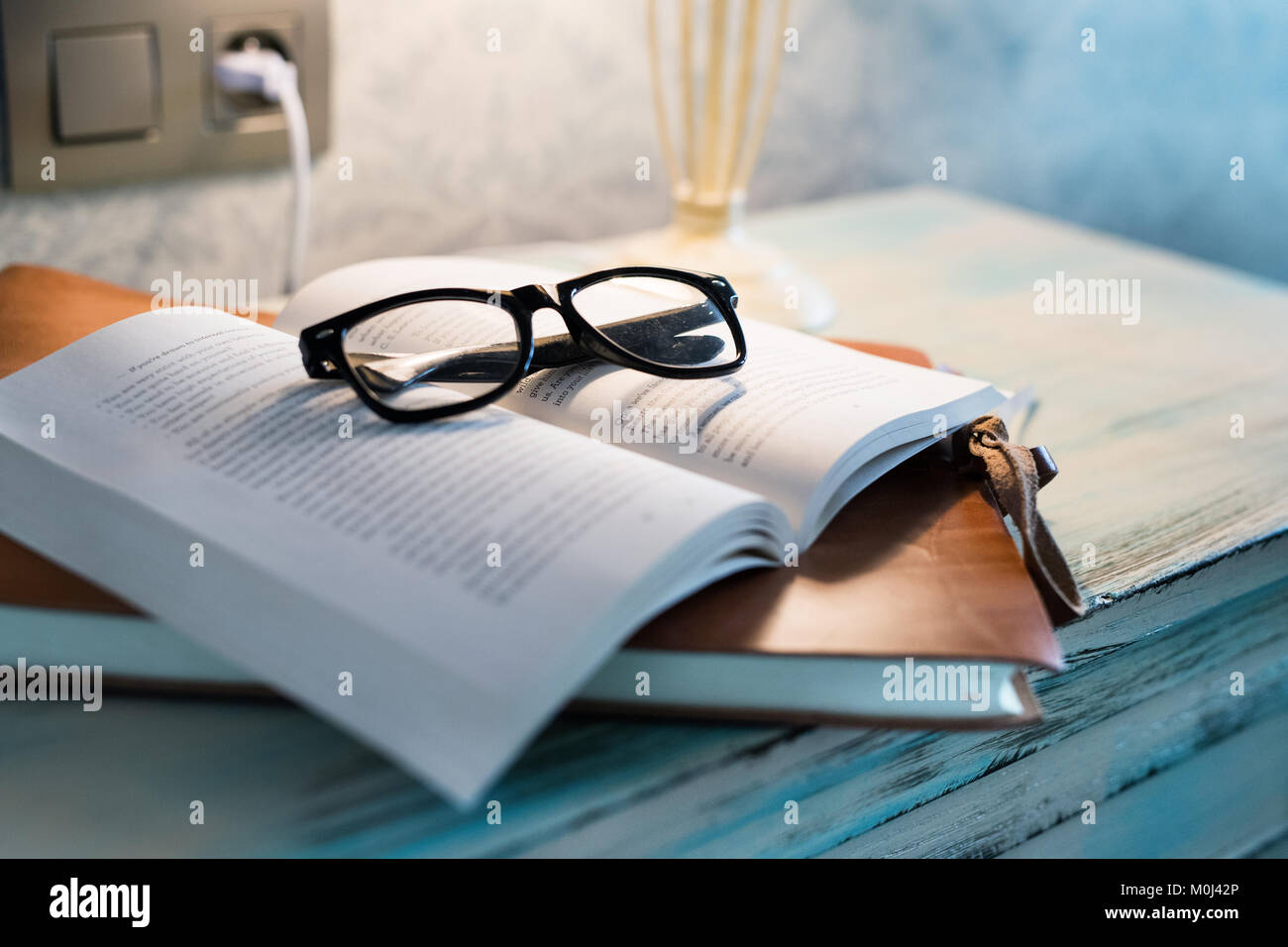 A lamp and a book on a bedside table in a hotel room Stock Photo - Alamy
