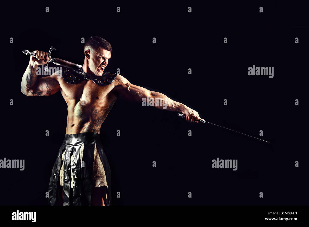 Portrait of handsome muscular gladiator with two swords. Studio shot ...