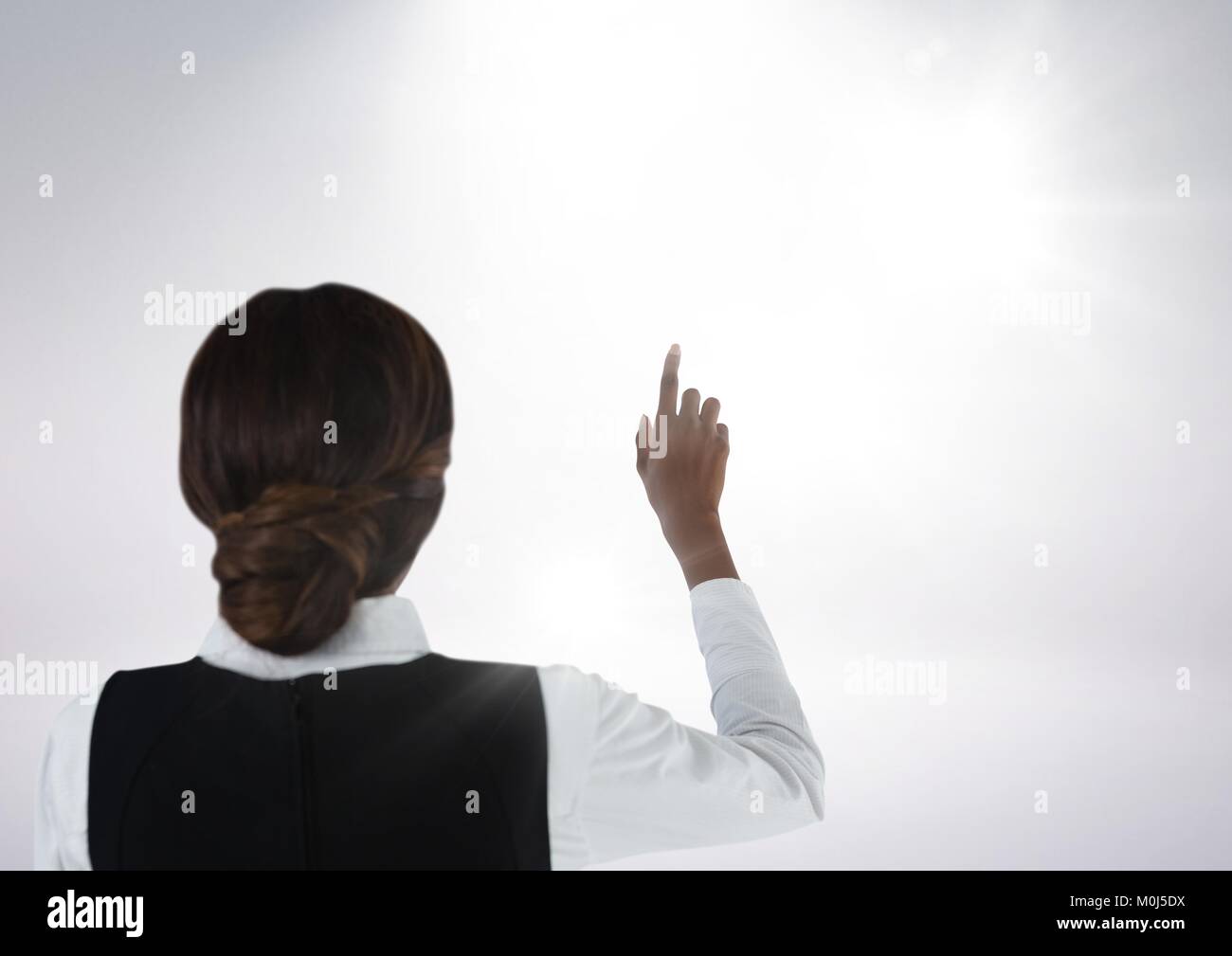 Businesswoman pointing at bright background Stock Photo - Alamy