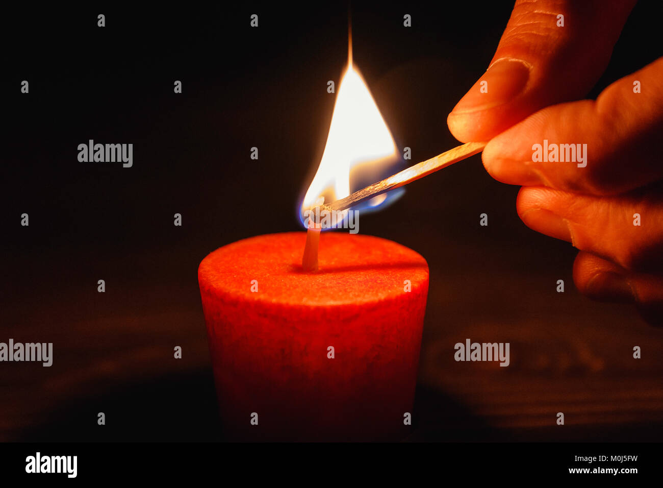 lighting candles in the dark. man's hand lights a candle with a match ...