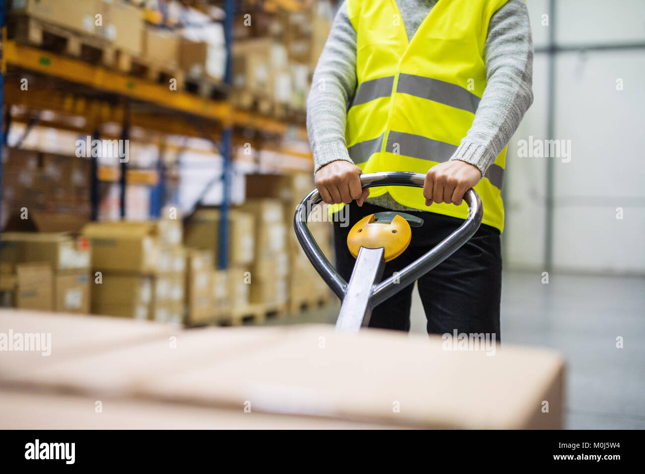 Male warehouse worker pulling a pallet truck Stock Photo - Alamy