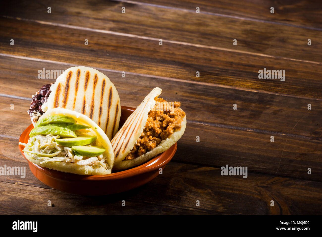Three types of arepas, Latin American food on wood table Stock Photo ...