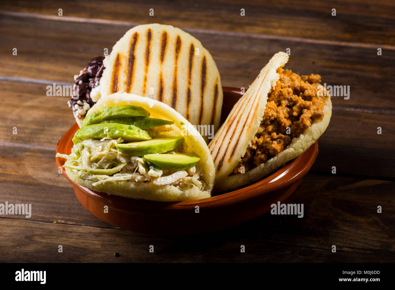 Three types of arepas, Latin American food on wood table Stock Photo ...