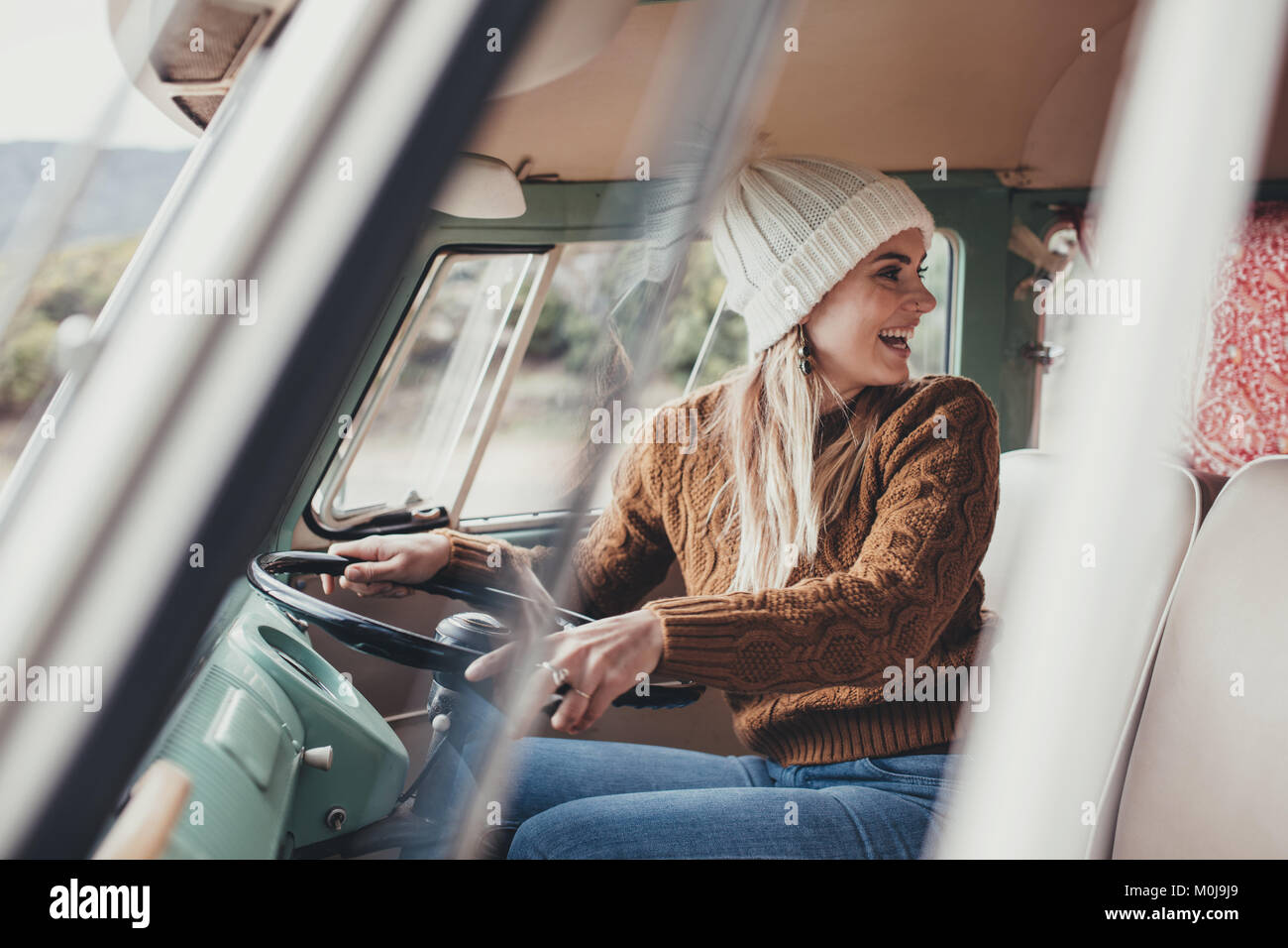 Beautiful woman on road trip driving a van. Smiling female travelling ...