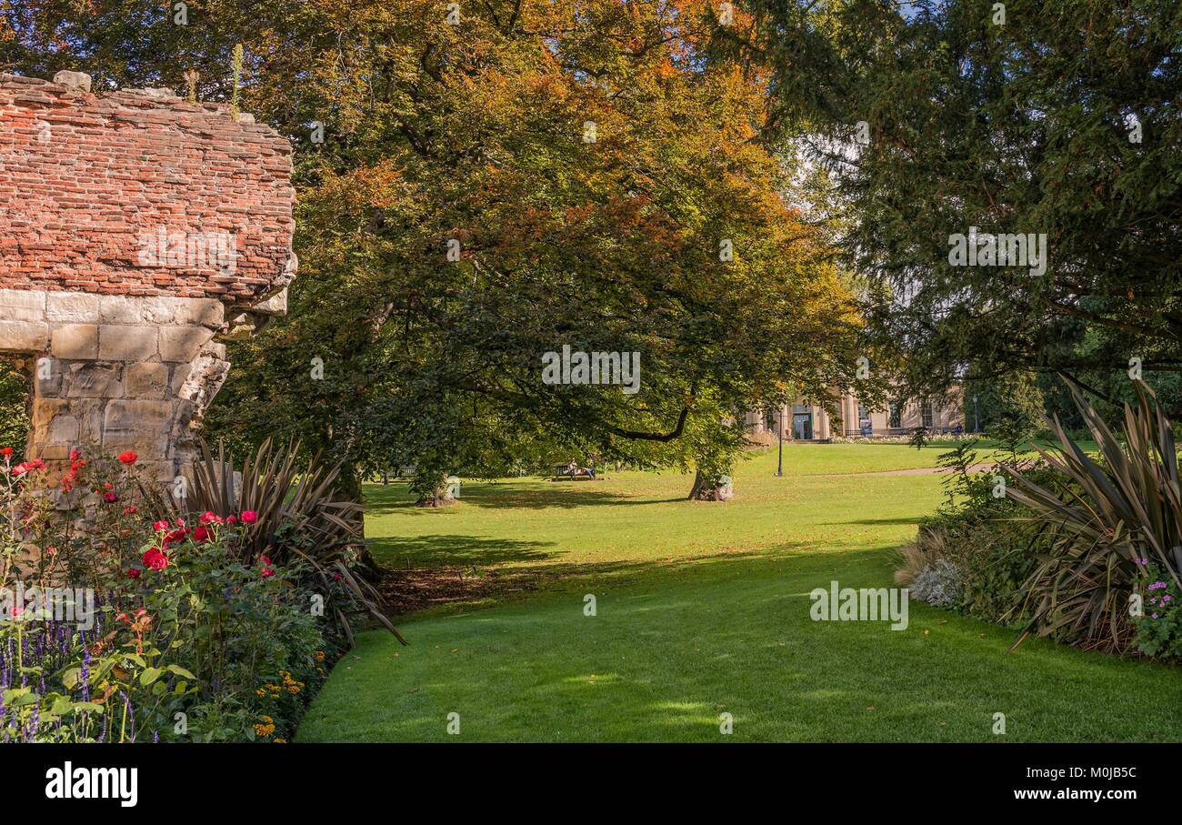 A lawn winds past an ancient ruin and a flower bed into a park Stock ...