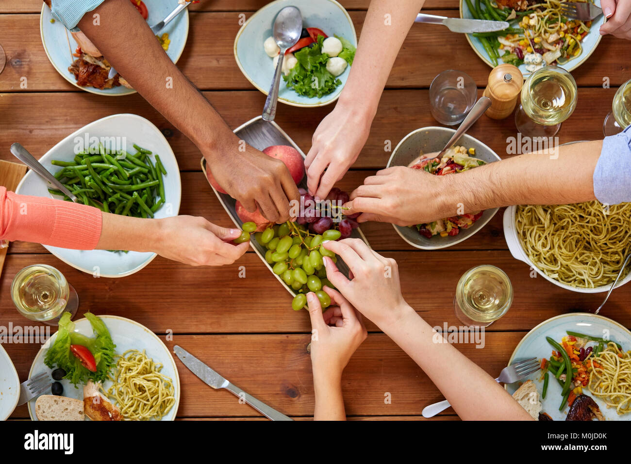 group of people eating at table with food Stock Photo - Alamy