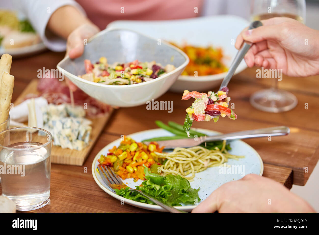 people eating salad at table with food Stock Photo - Alamy