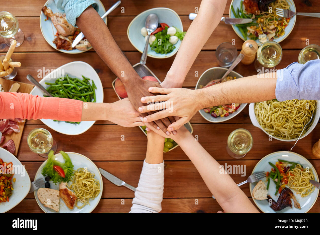 people holding hands together over table with food Stock Photo - Alamy