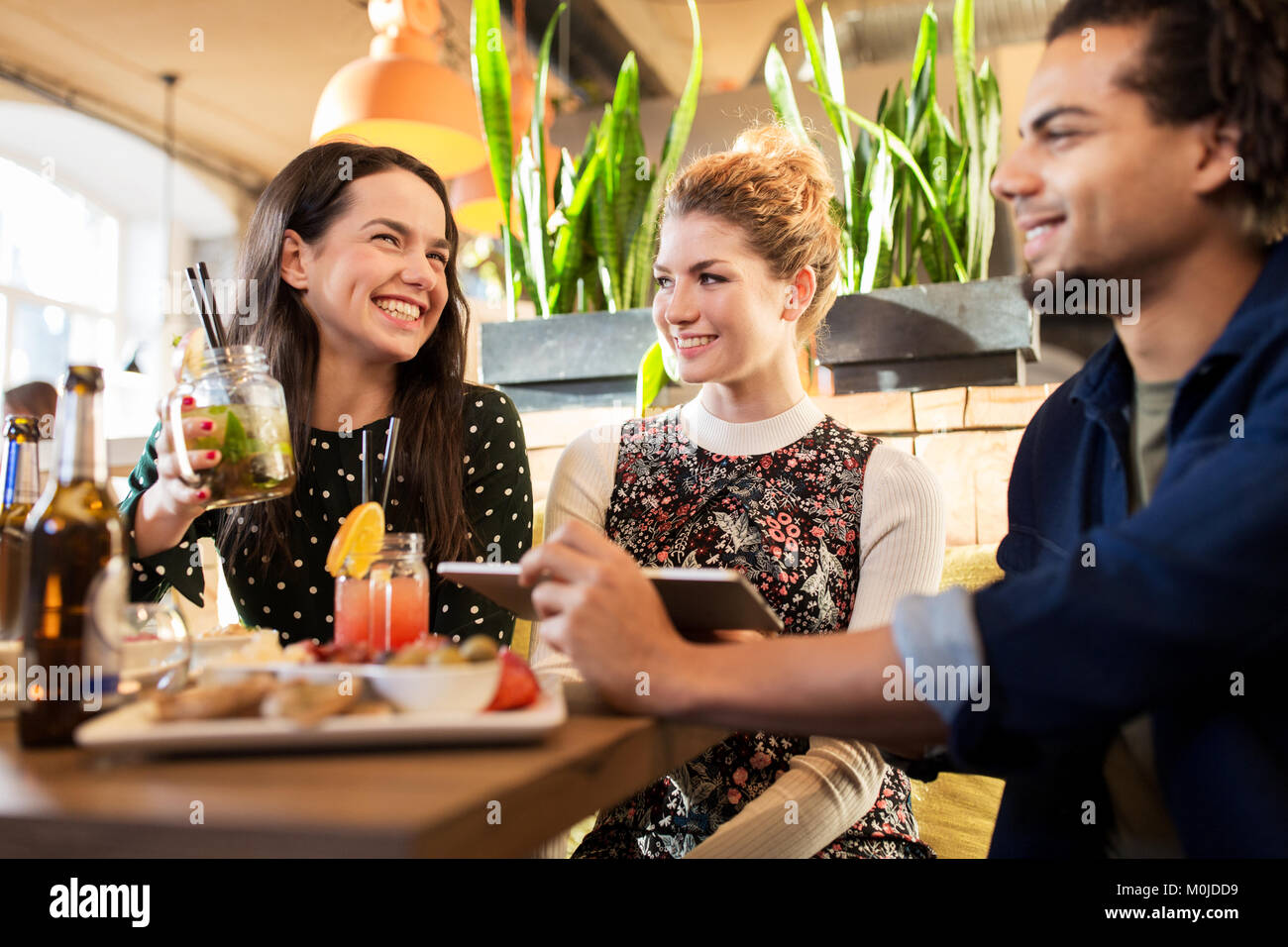 happy friends eating and drinking at bar or cafe Stock Photo - Alamy