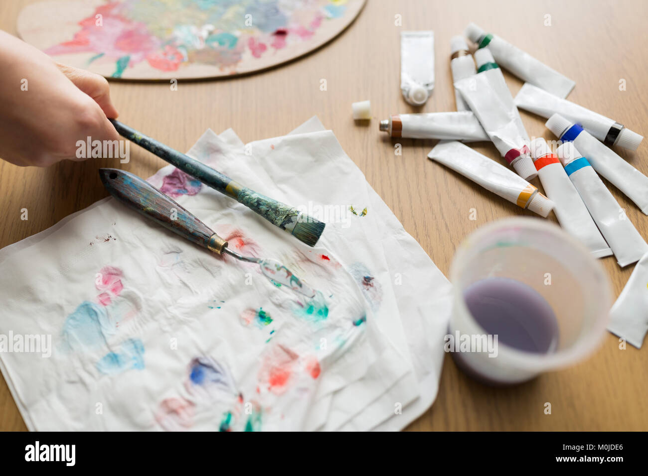 artist hand with paintbrush, paper and paint tubes Stock Photo - Alamy
