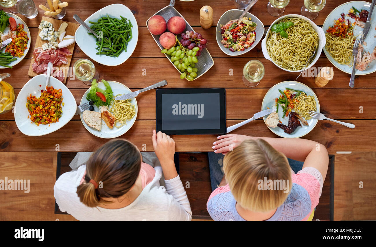 women with tablet pc at table full of food Stock Photo - Alamy