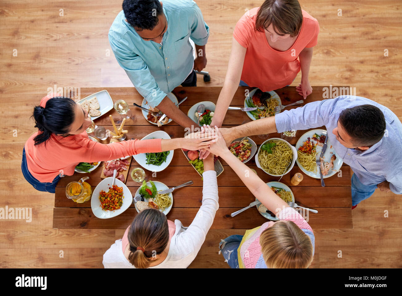 people holding hands together over table with food Stock Photo - Alamy