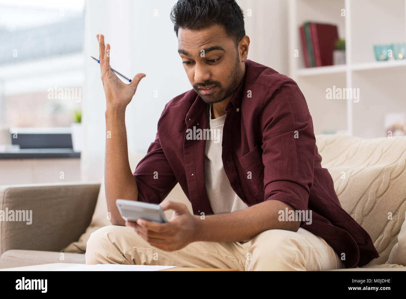 confused man with calculator at home Stock Photo - Alamy