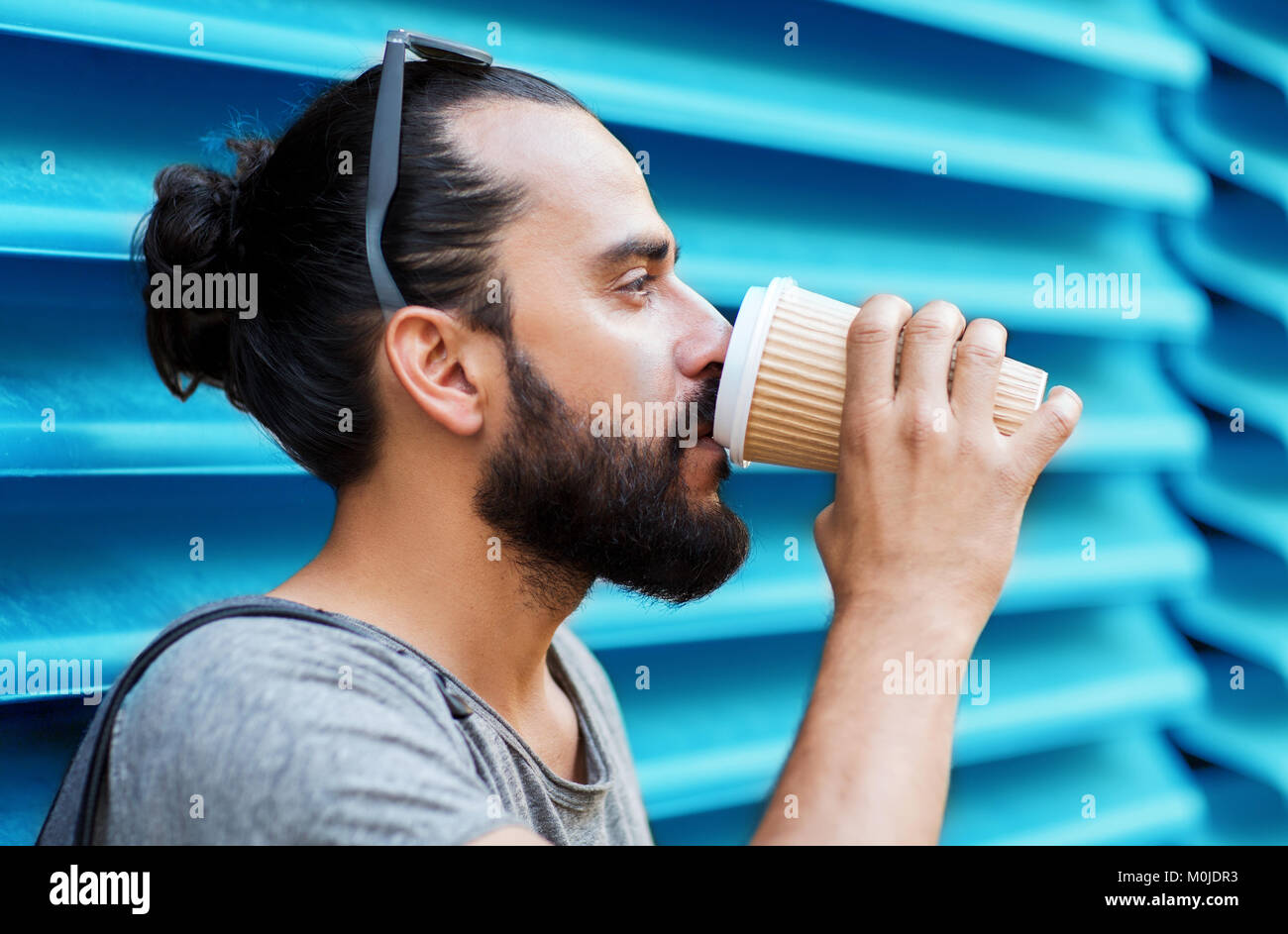 man drinking coffee from paper cup over wall Stock Photo - Alamy