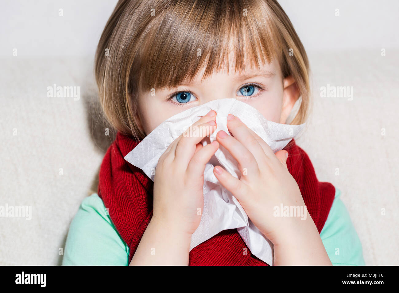 kid cleaning nose with tissue on white background Stock Photo - Alamy