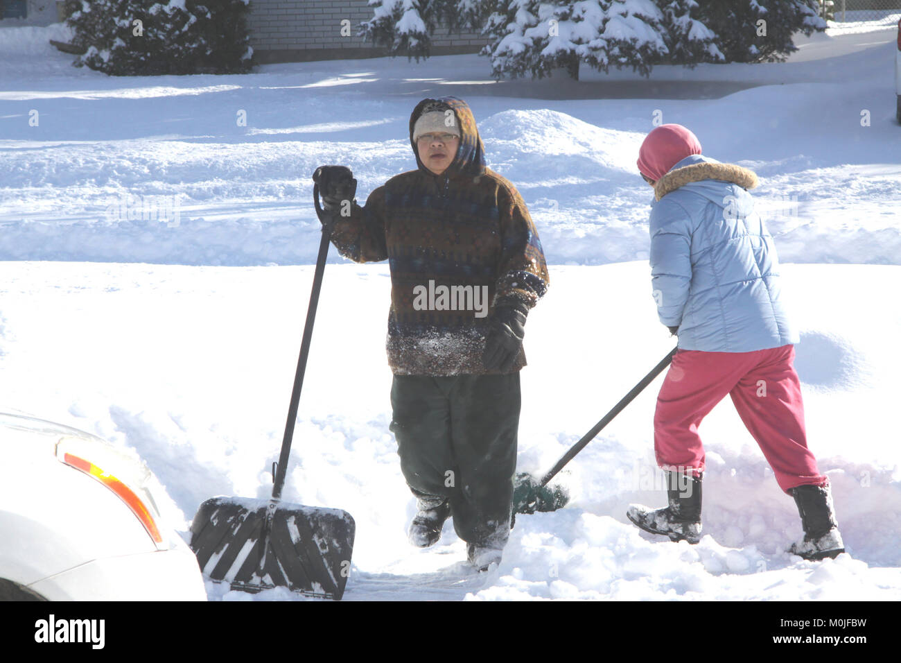 Ladies with shovels in the deep snow in the driveway after a big snow ...