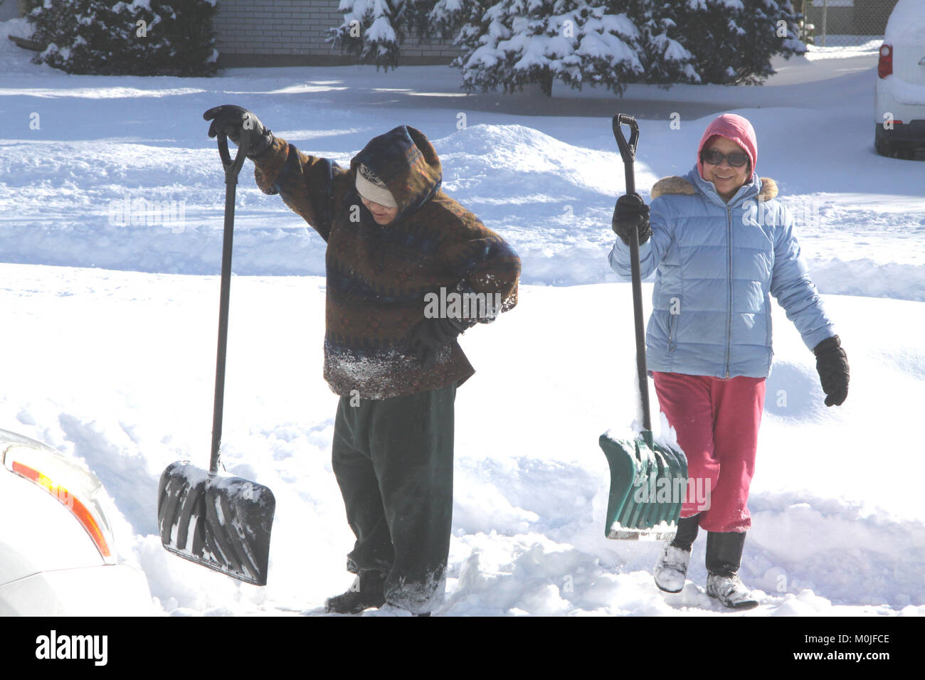 Ladies with shovels in the deep snow in the driveway after a big snow ...