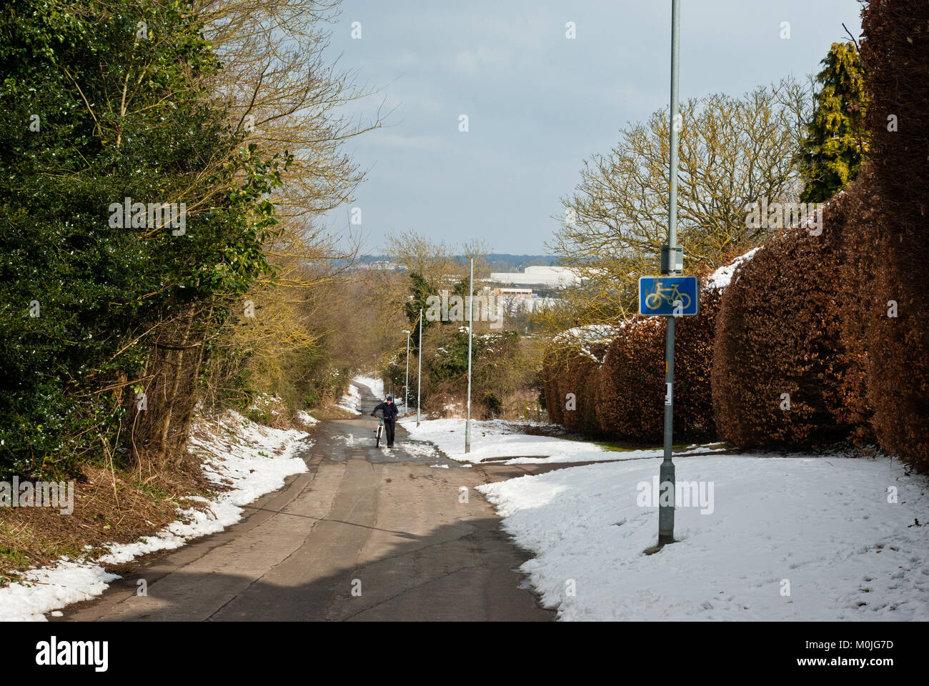 A male cyclist pushes his bike up a steep cycle path in Winter ...