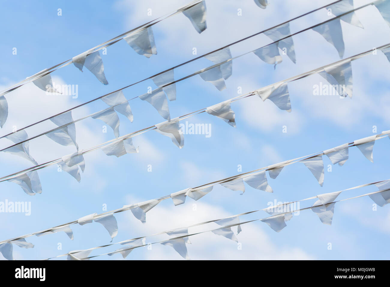 Garland of white flags of triangular shape, pennants in blue sky. City ...