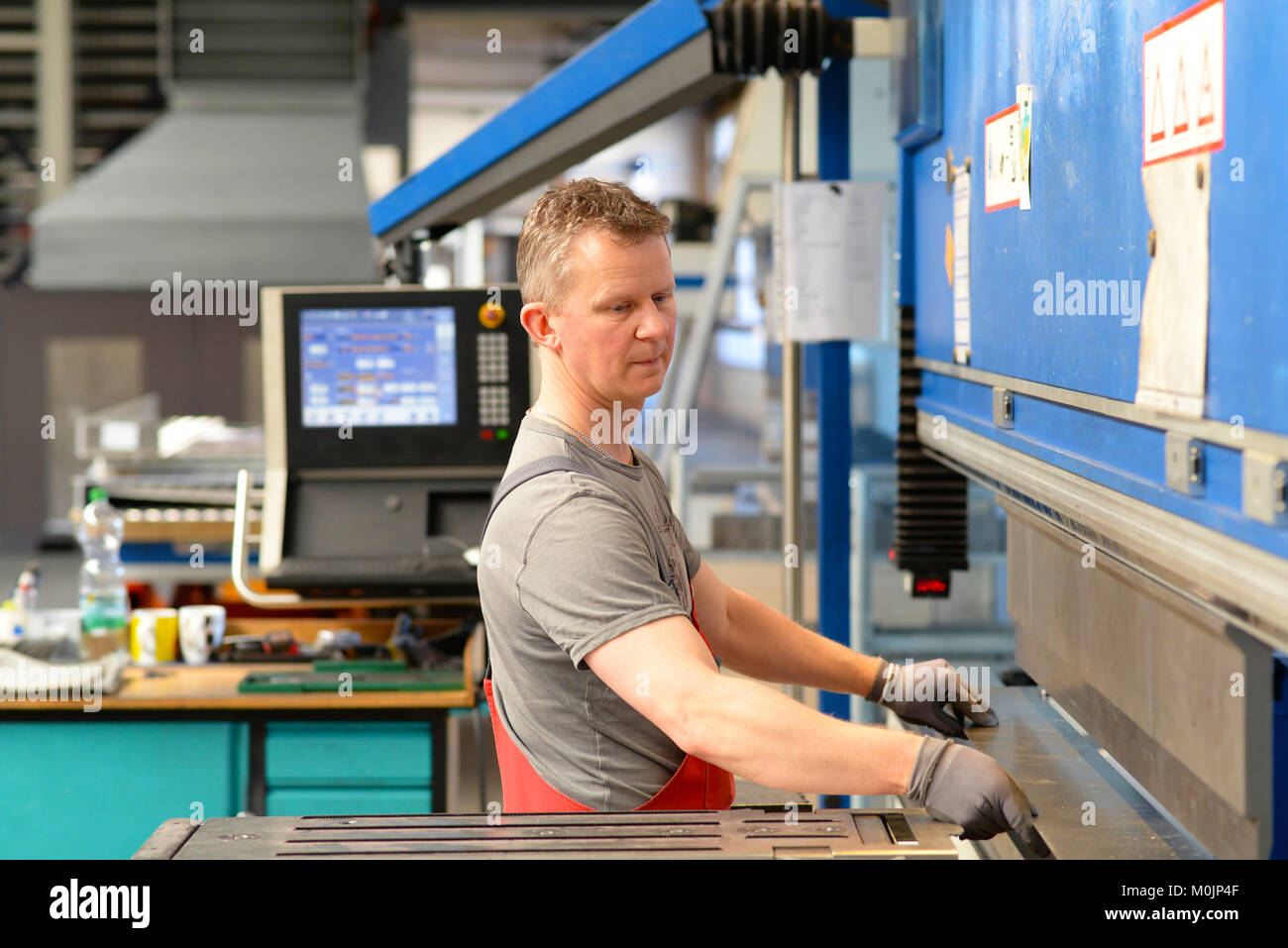employee operates bending machine in a metalworking company - bending ...