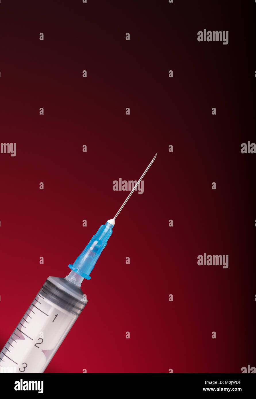 Isolated medical syringe on red, dark background Stock Photo - Alamy