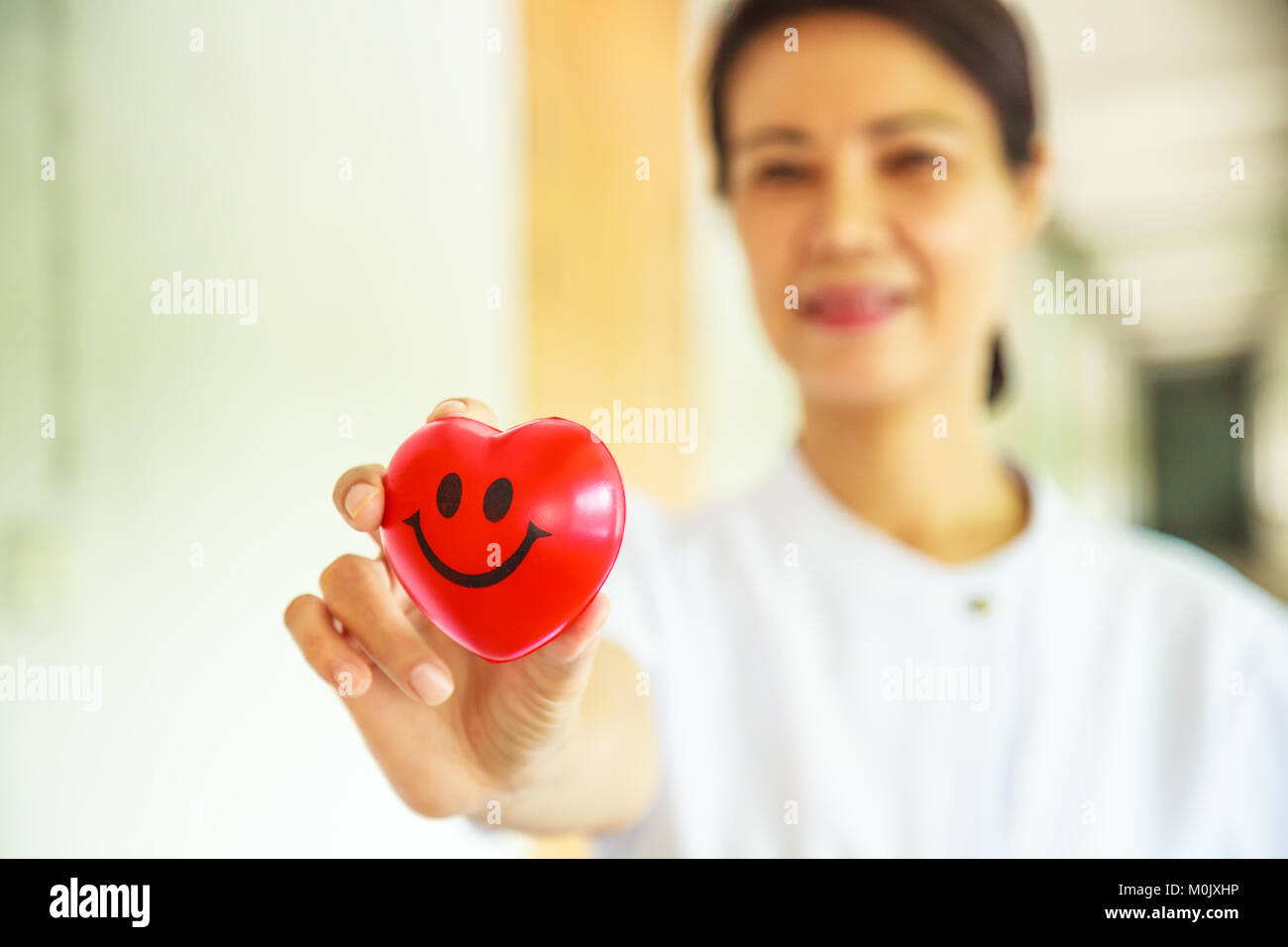 Red smiling heart held by smiling female nurse's hand, representing ...