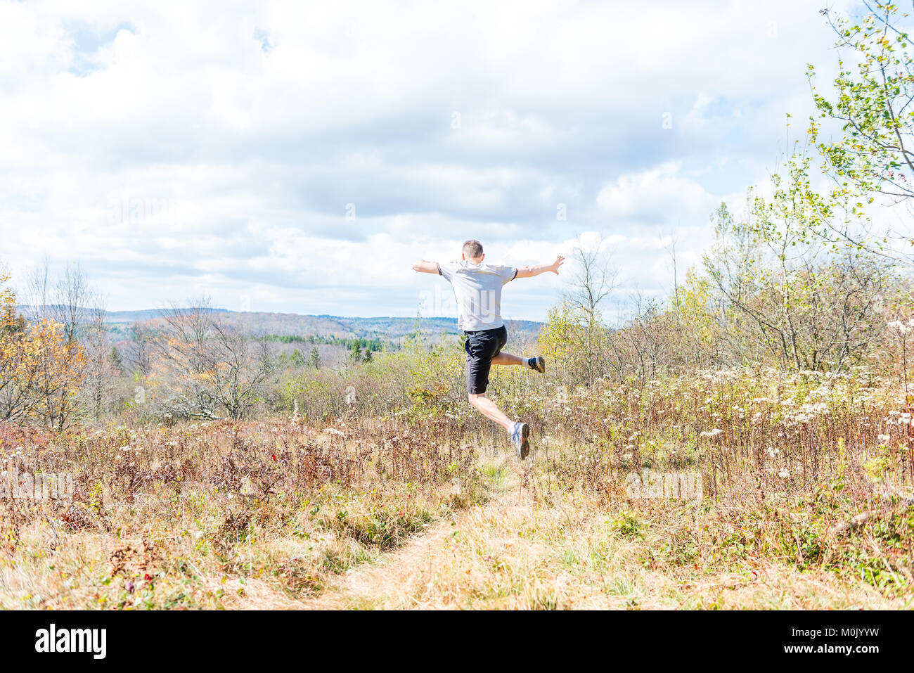 Young athletic, fit, free happy man running jogging jumping in autumn ...