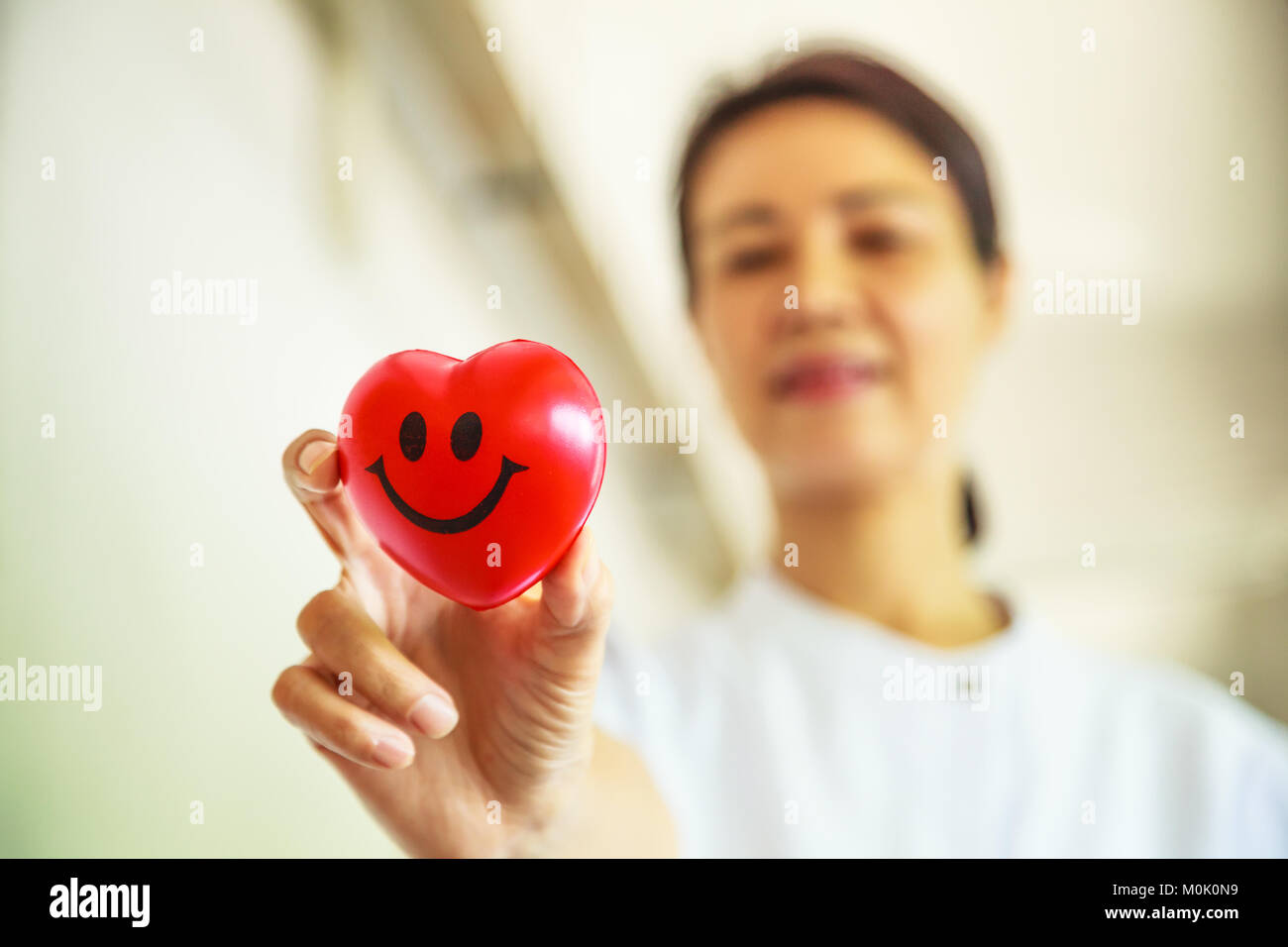 Red smiling heart held by smiling female nurse's hand, representing ...