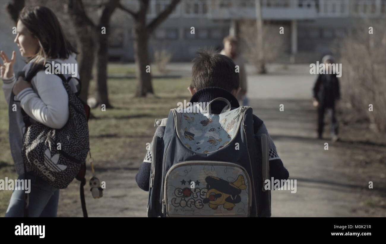 Rear side view of child carrying backpack going to or from school on ...