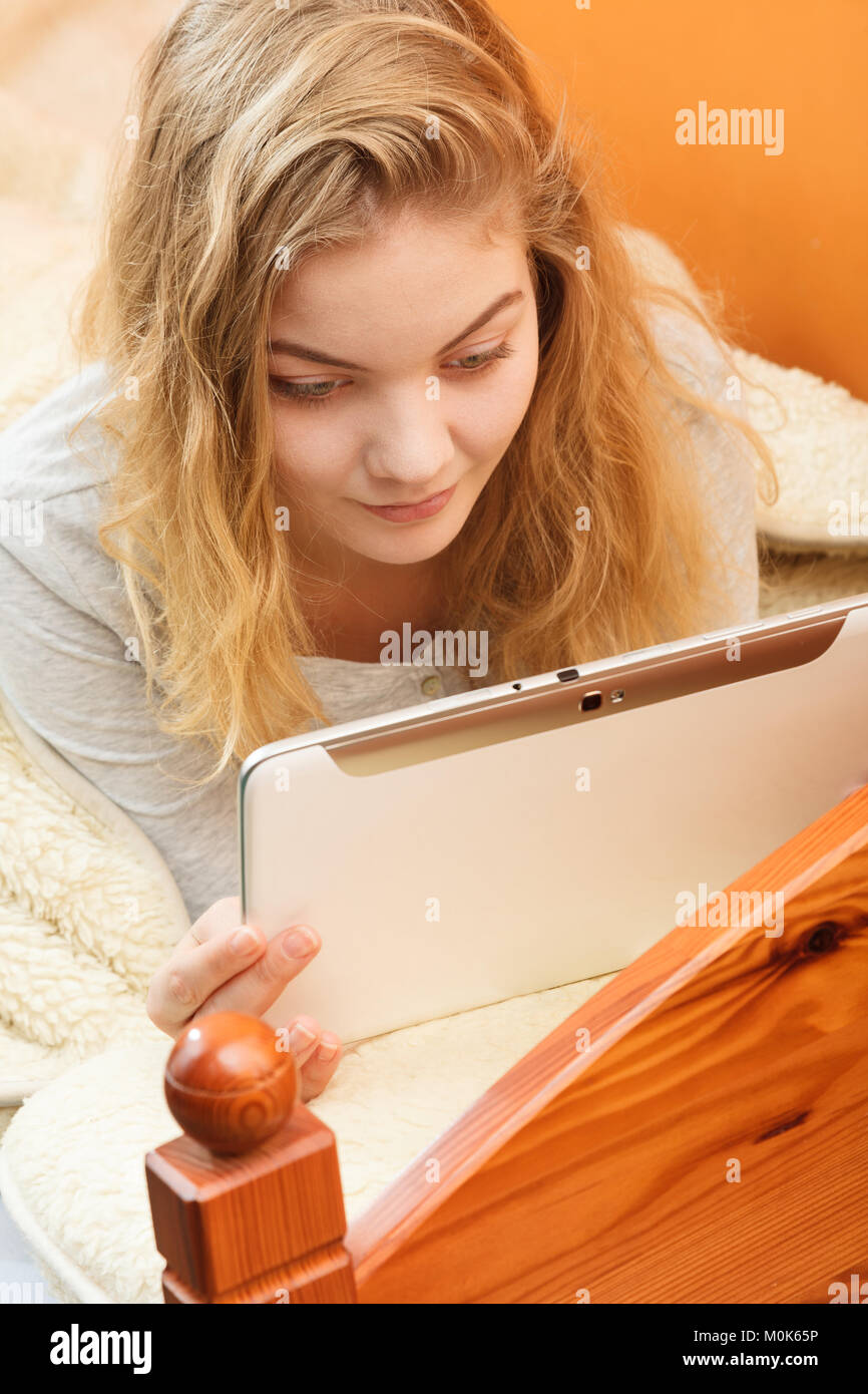 Lazy young woman using computer tablet browsing internet. Girl laying ...