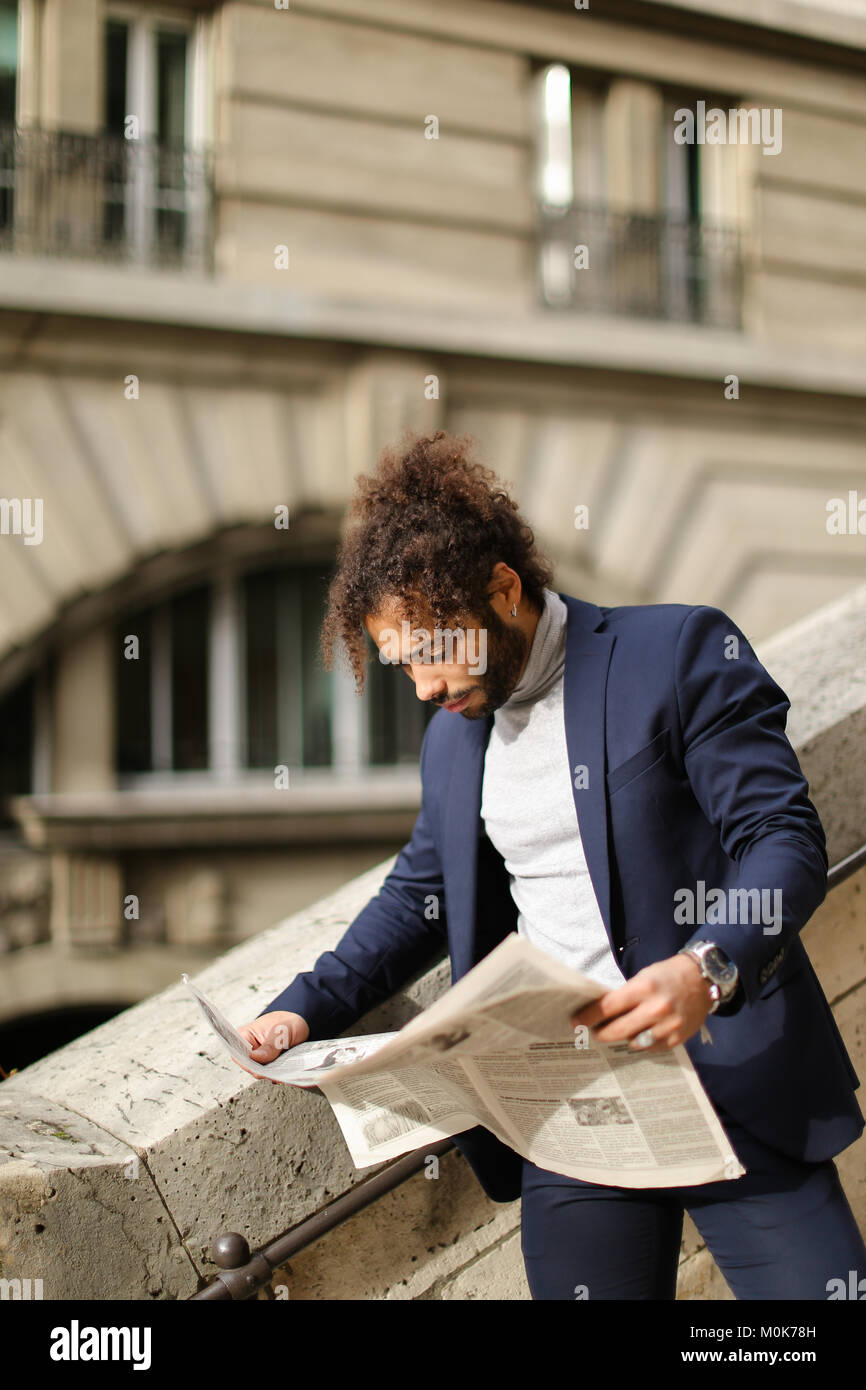 Upset guy reading newspaper outdoor Stock Photo - Alamy