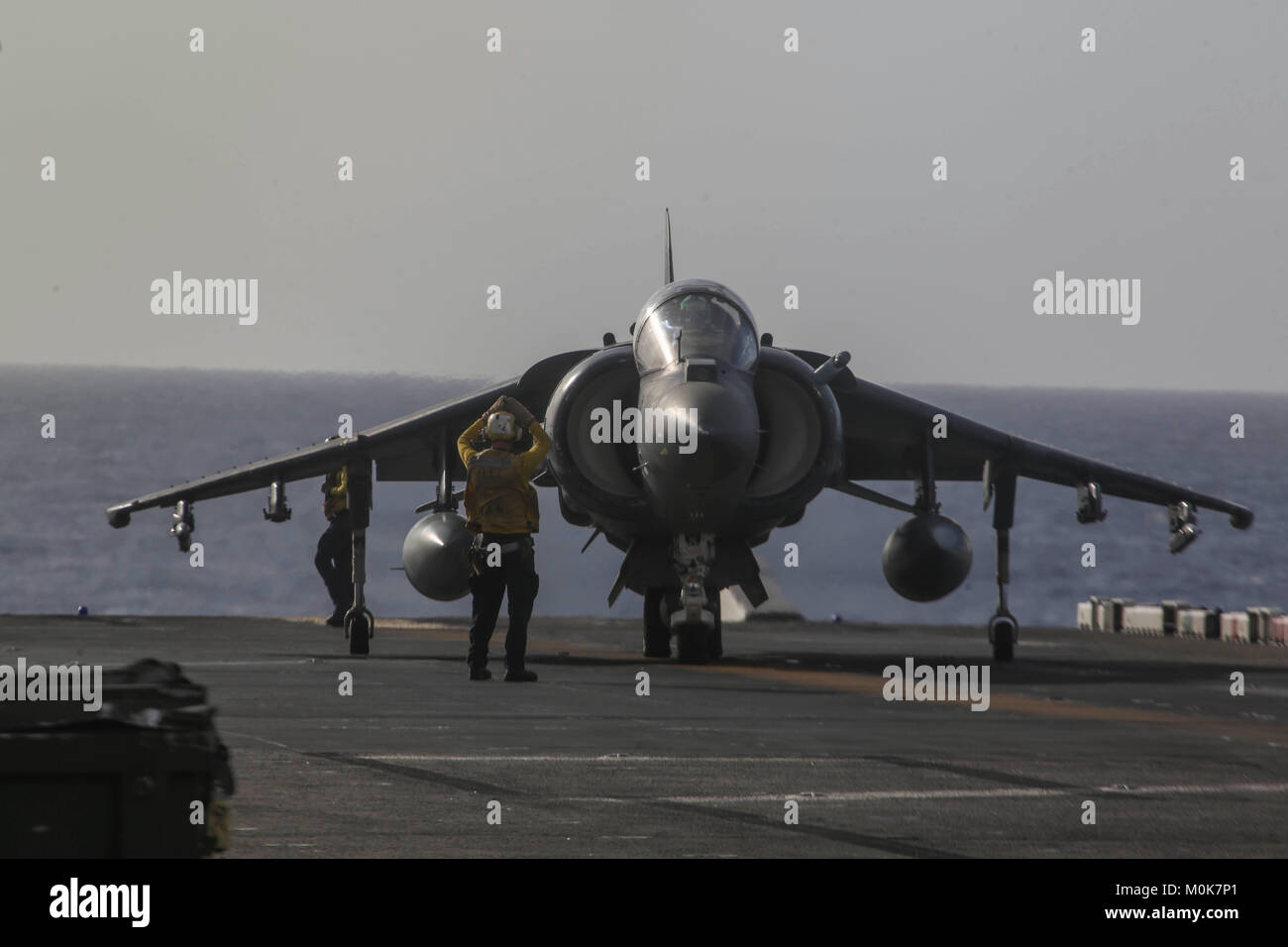 An aircraft handler directs an AV-8B Harrier into position for takeoff ...