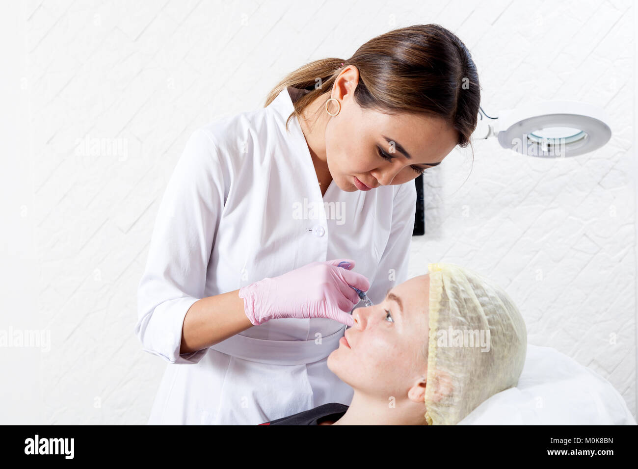 Close-up Young woman doctor cosmetician in white lab coat and sterile ...
