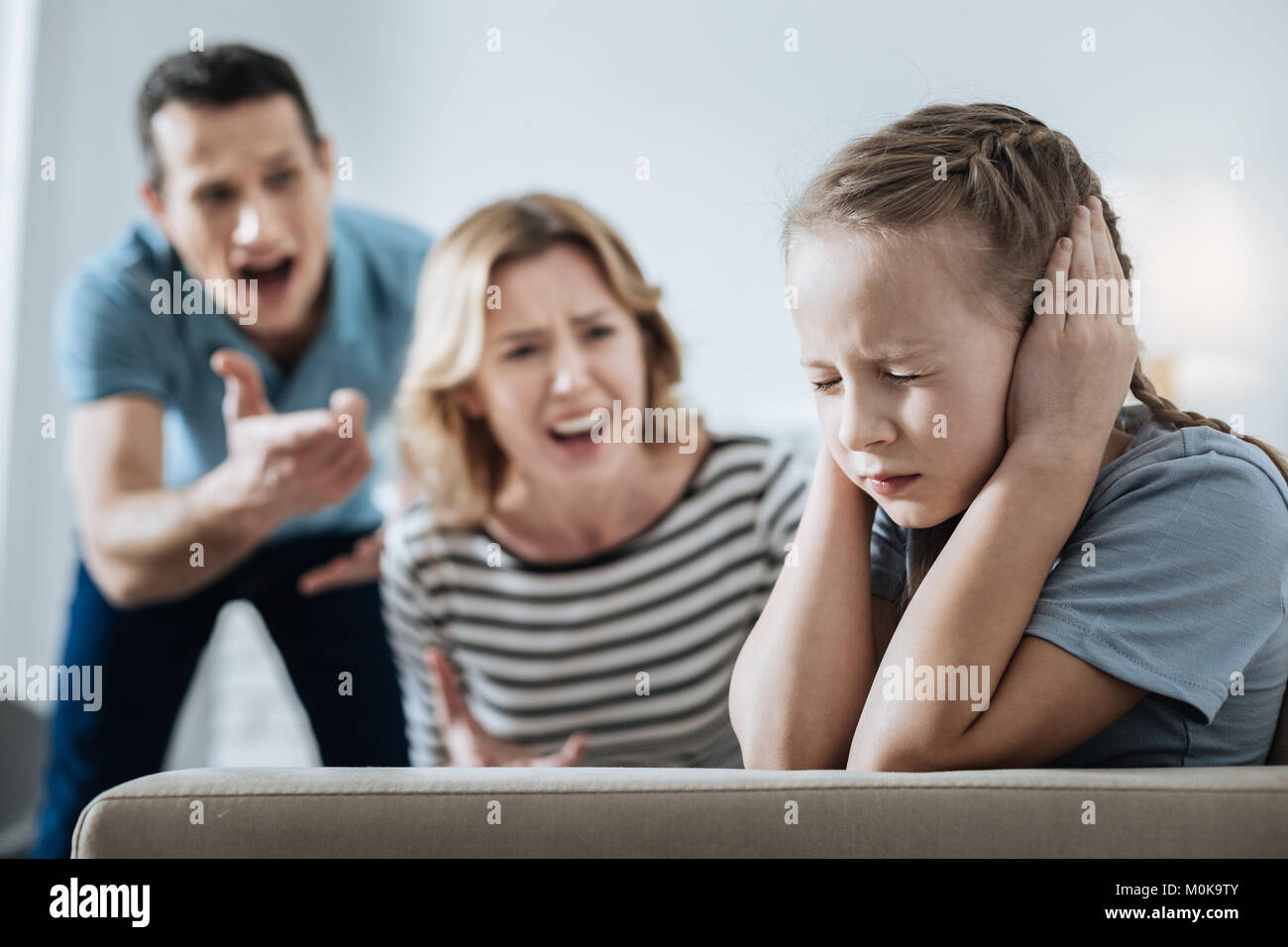 Sad girl and her parents shouting at her Stock Photo - Alamy