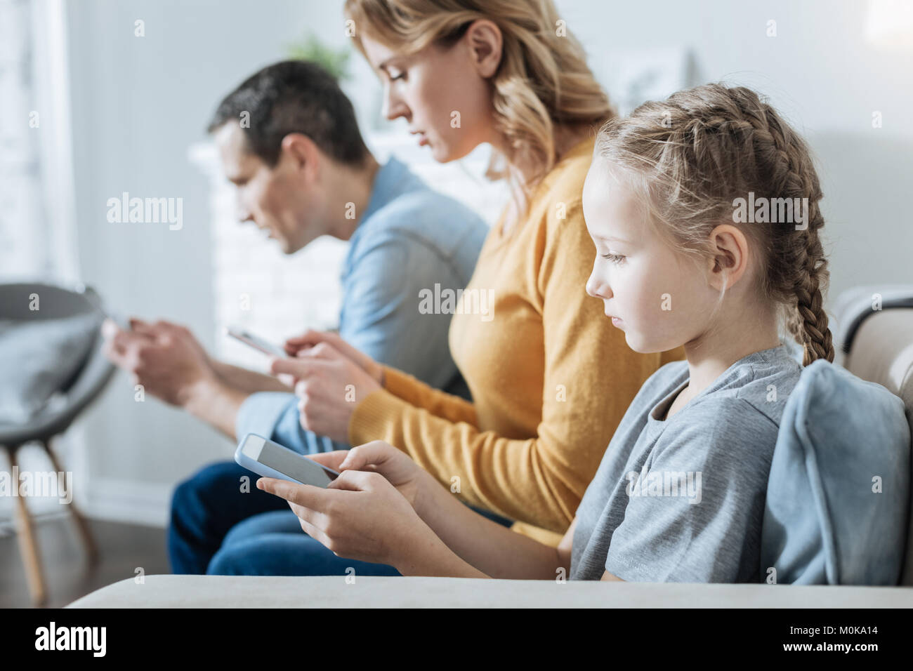 Serious little girl and her parents using phones Stock Photo - Alamy