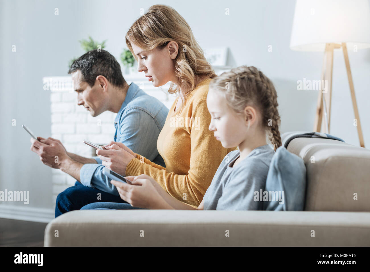 Concentrated little girl and her parents using phones Stock Photo - Alamy