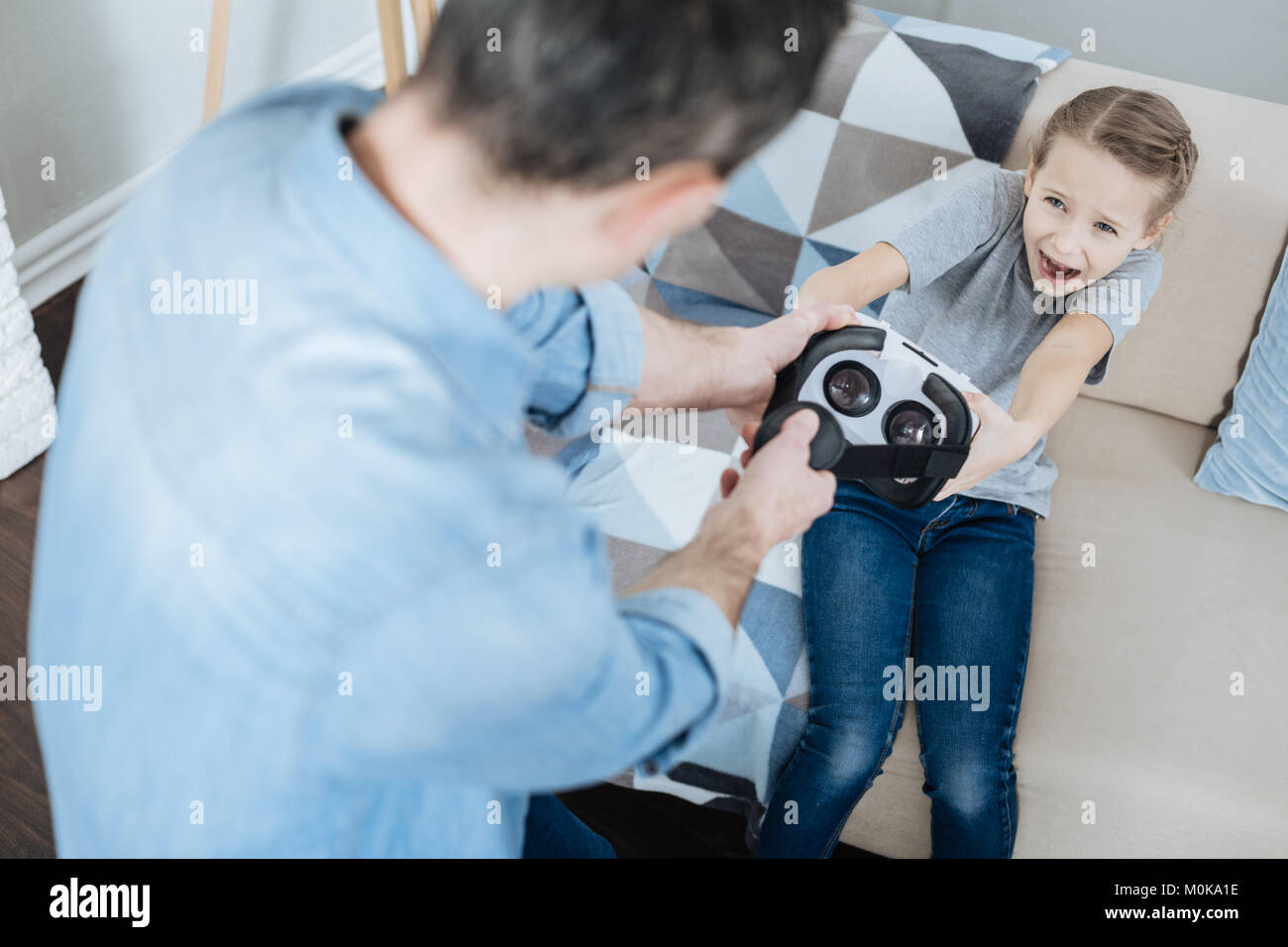 Annoyed little girl shouting and holding her VR headset Stock Photo - Alamy