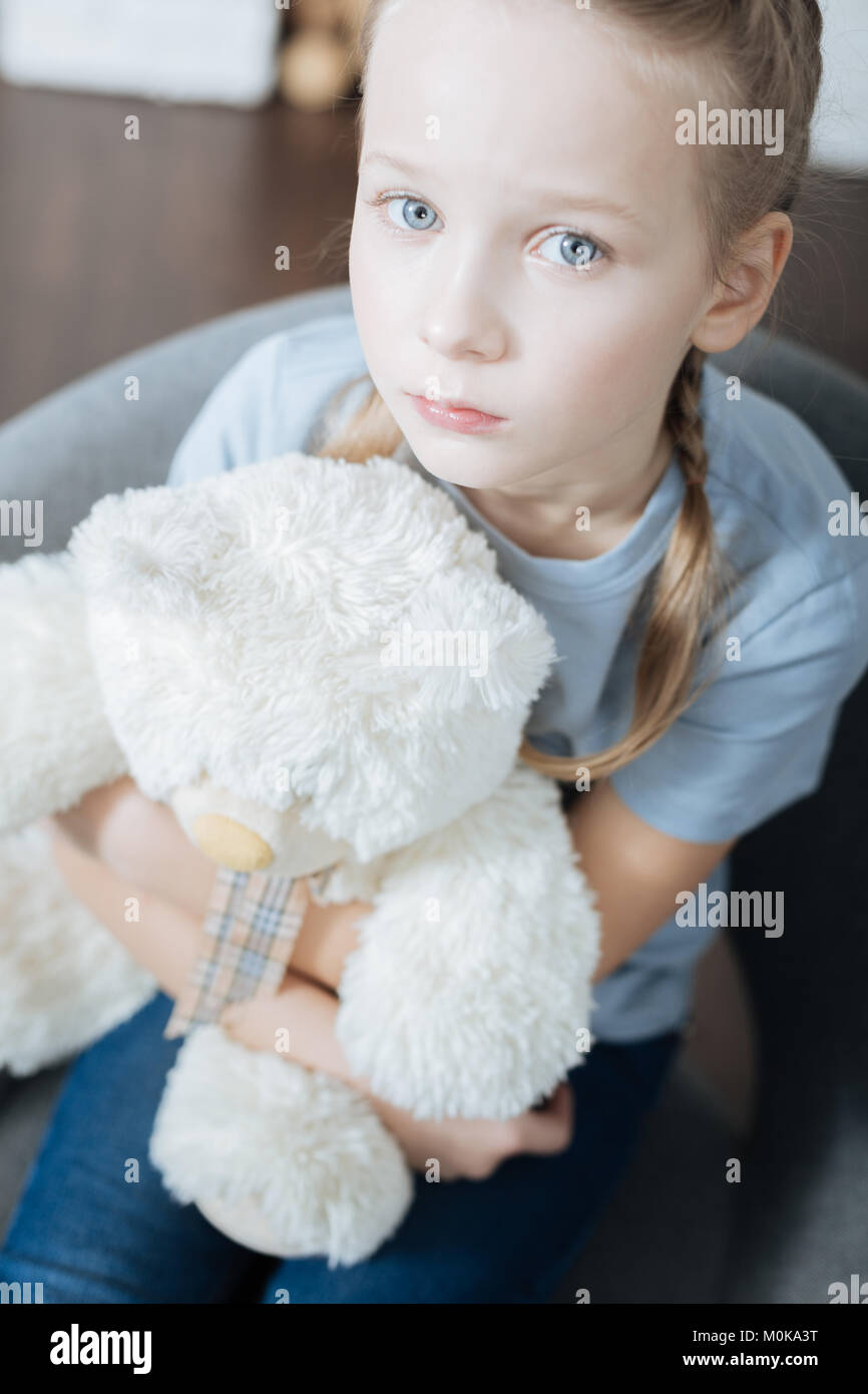 Unhappy kid holding her favourite toy Stock Photo - Alamy