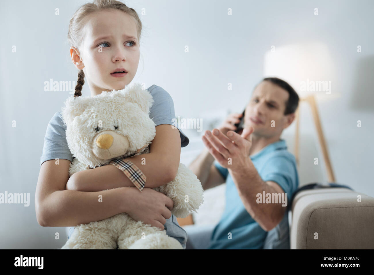 Miserable little girl crying and holding her toy Stock Photo - Alamy