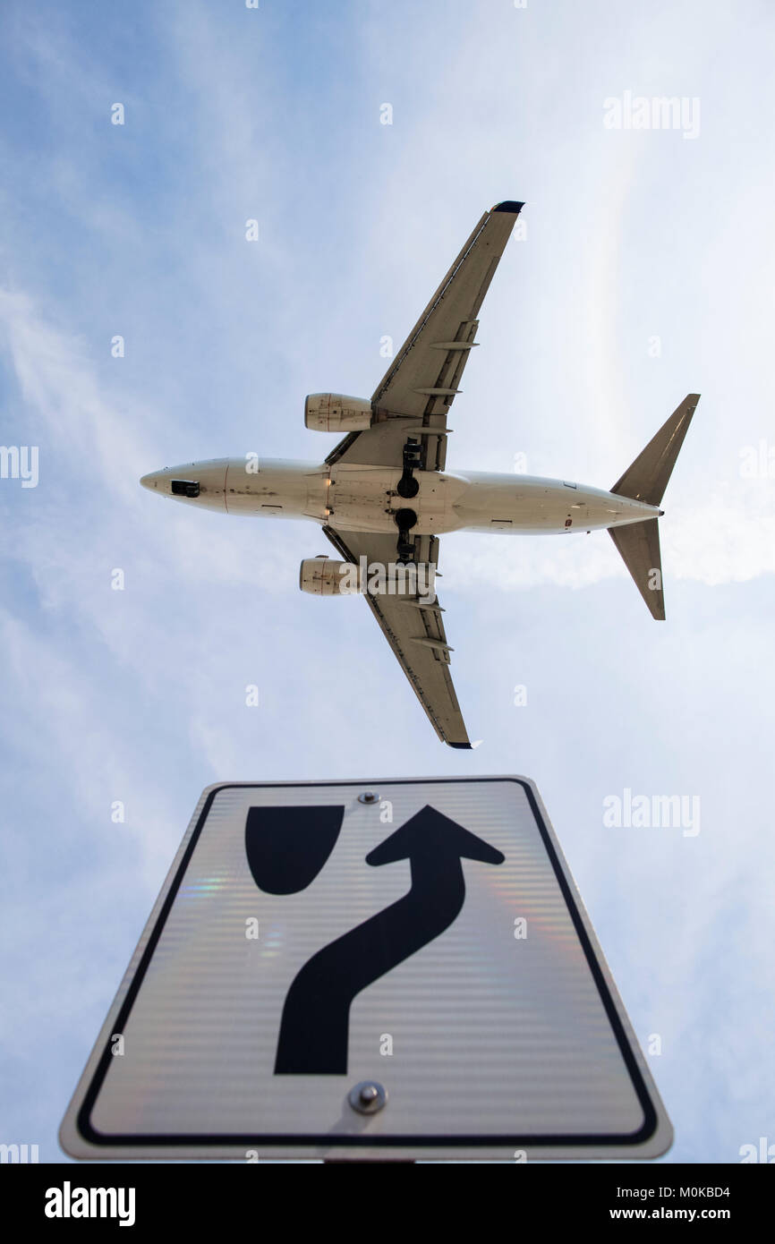 Boeing 737-7CT aircraft on final approach passes over a road sign ...
