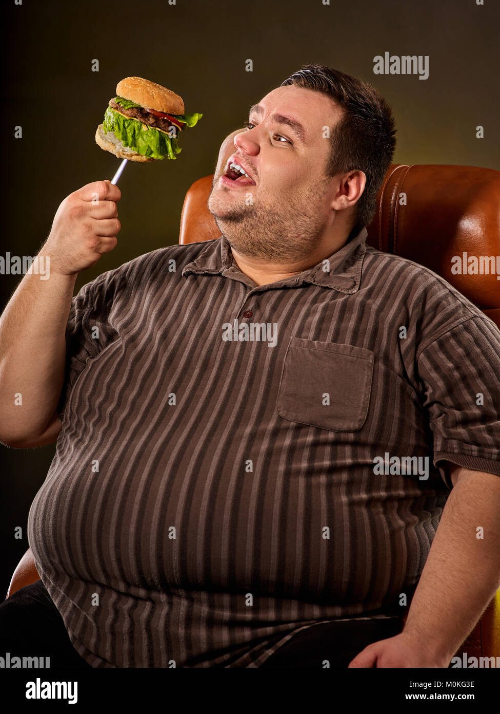 Fat man eating fast food hamberger. Breakfast for overweight person ...