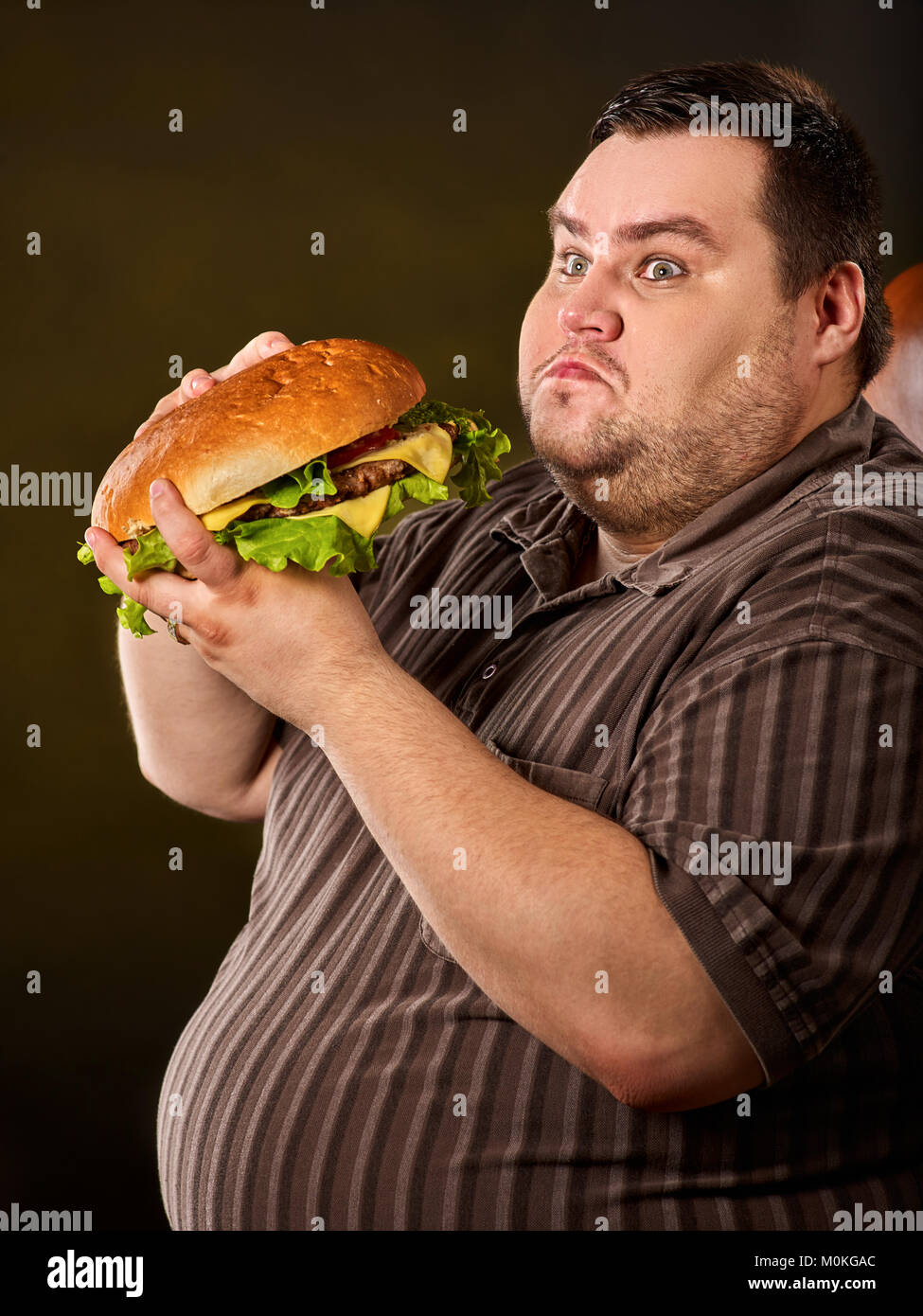 Fat man eating fast food hamberger. Breakfast for overweight person ...
