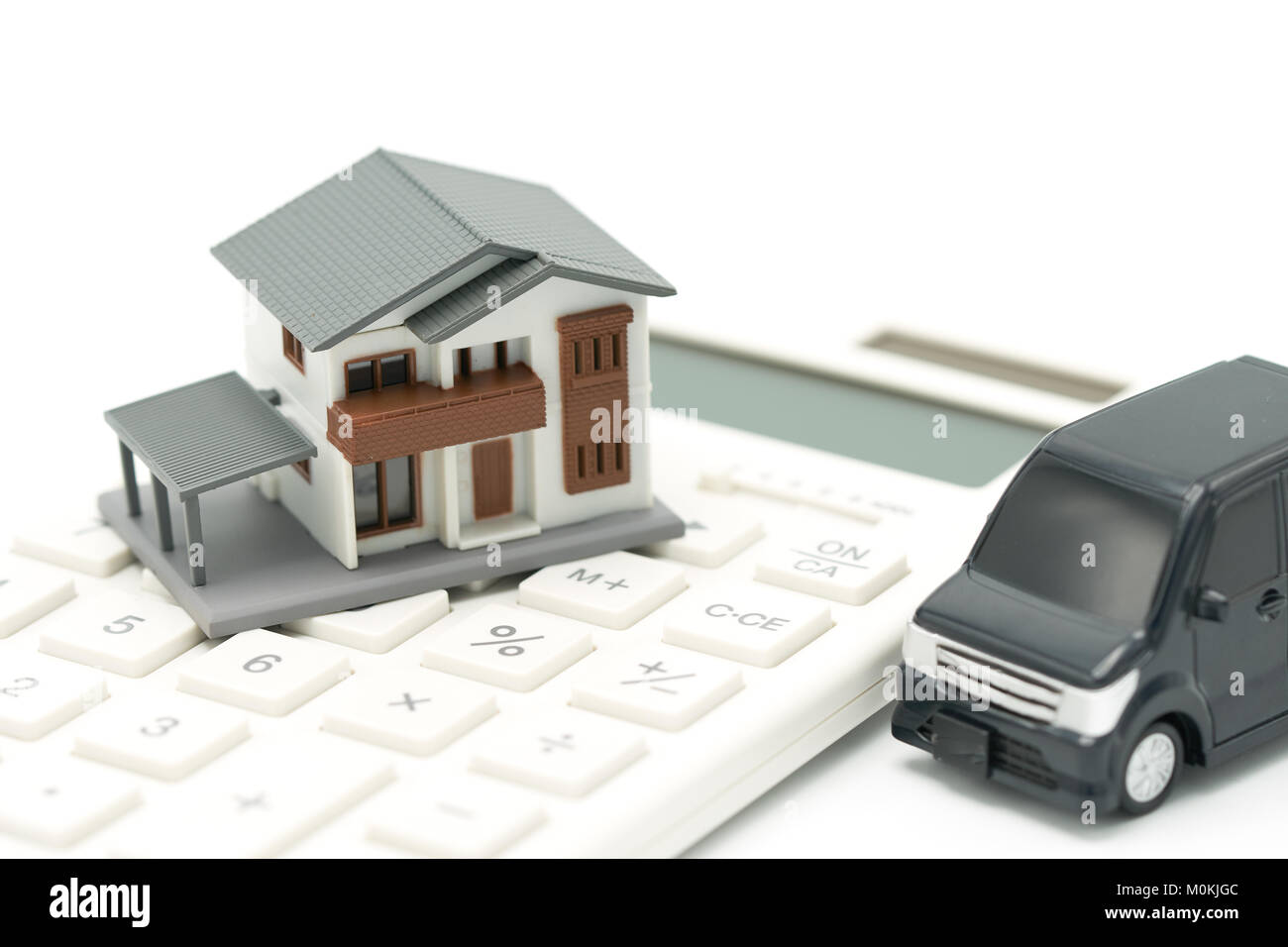 A model house model and car model is placed on a calculator. as ...