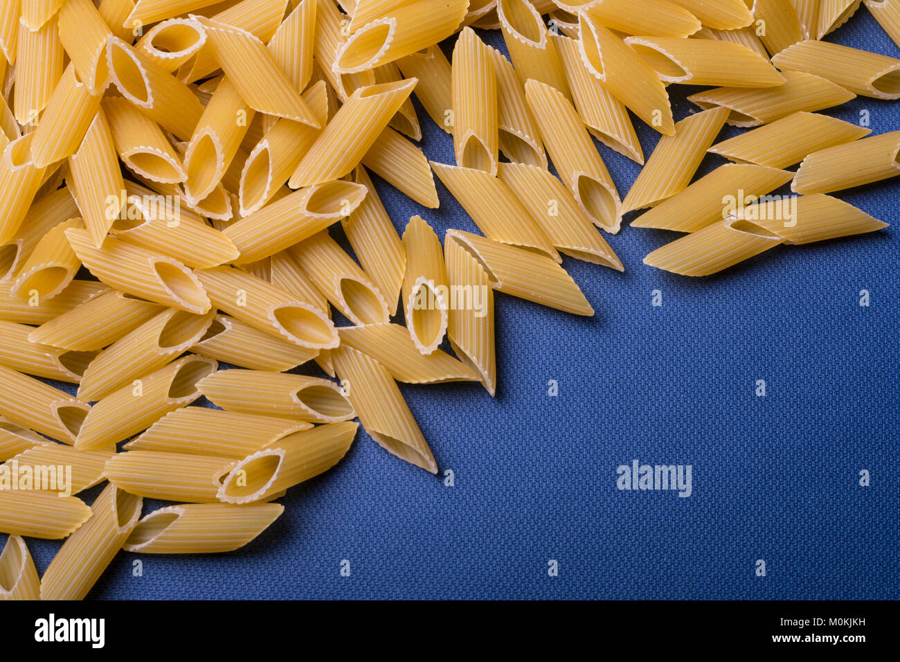 Tubular penne pasta on blue background. Food background, Top view Stock ...