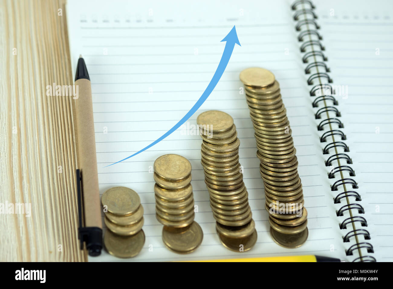 Steps of coins stack with notebook paper on wooden working table with ...