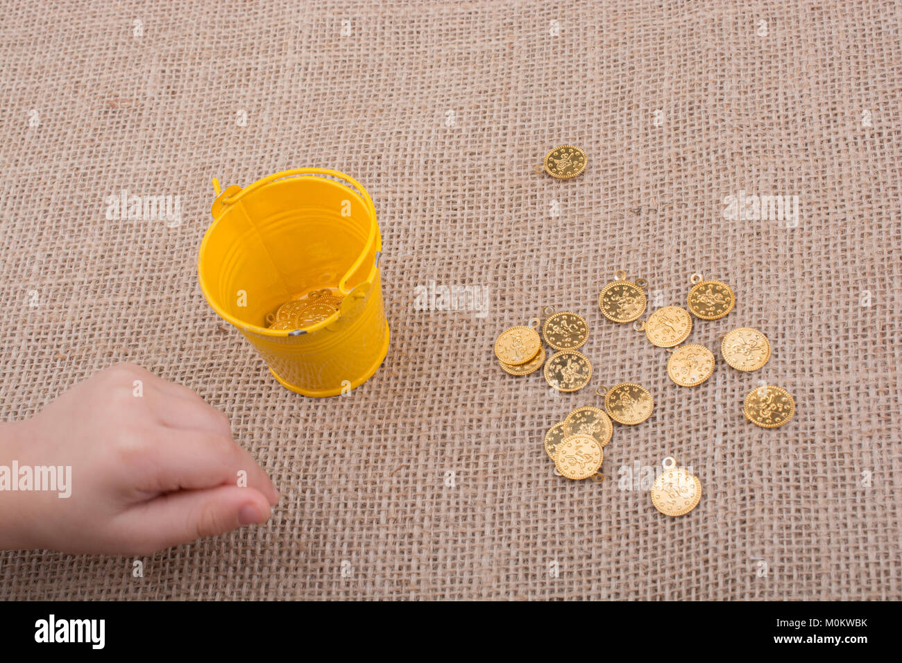 Bucket and fake gold coins in hand on canvas background Stock Photo - Alamy