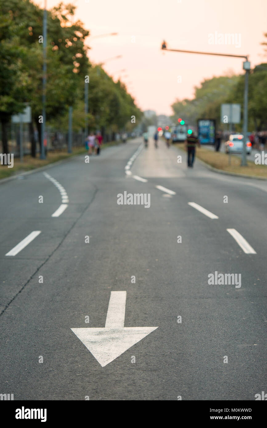 Empty street without traffic with arrow road sign in foreignground ...