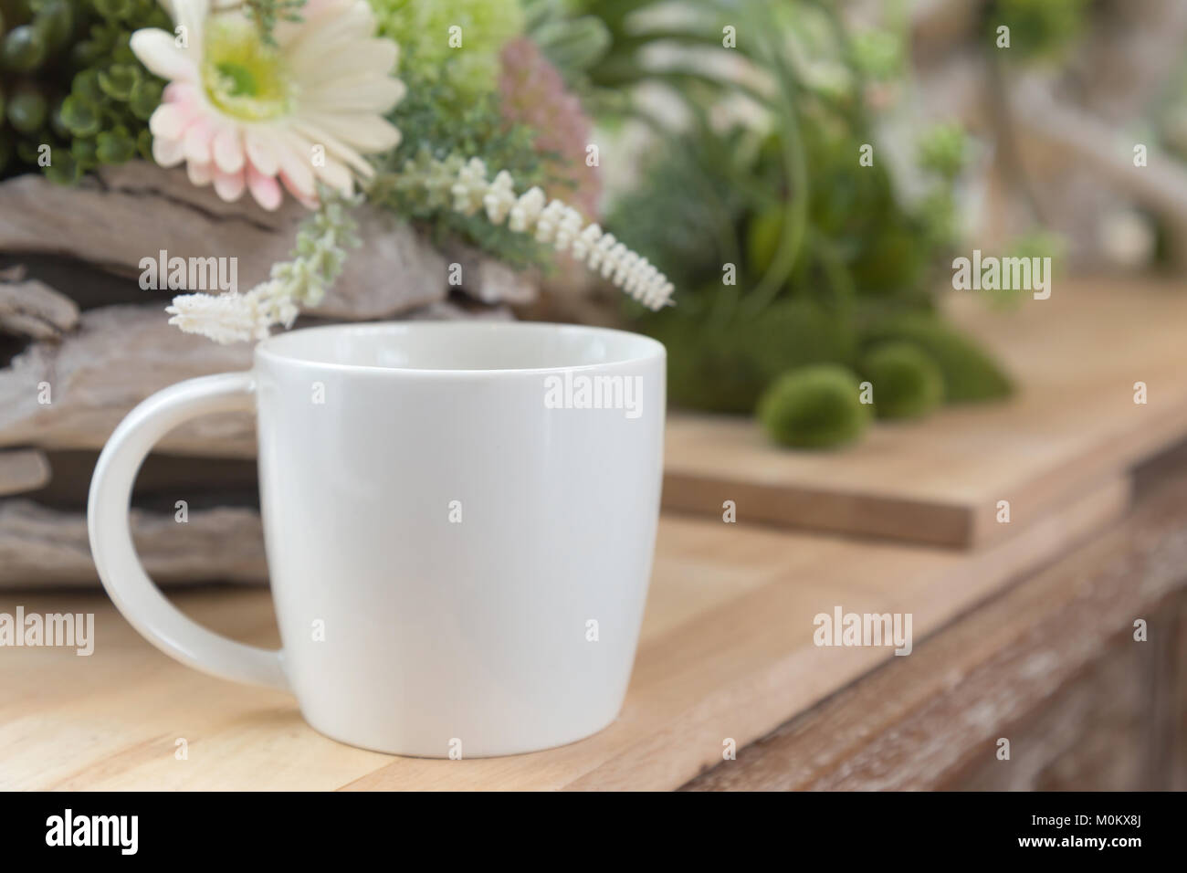 white coffee mug on wooden table in the garden at the coffee shop with ...