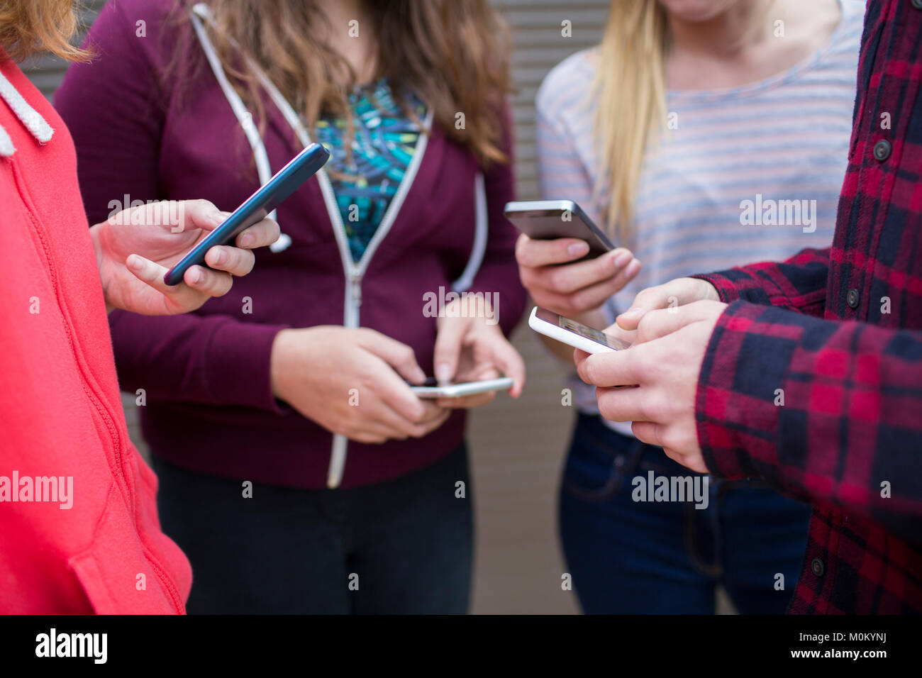 Group Of Teenagers Sharing Text Message On Mobile Phones Stock Photo ...